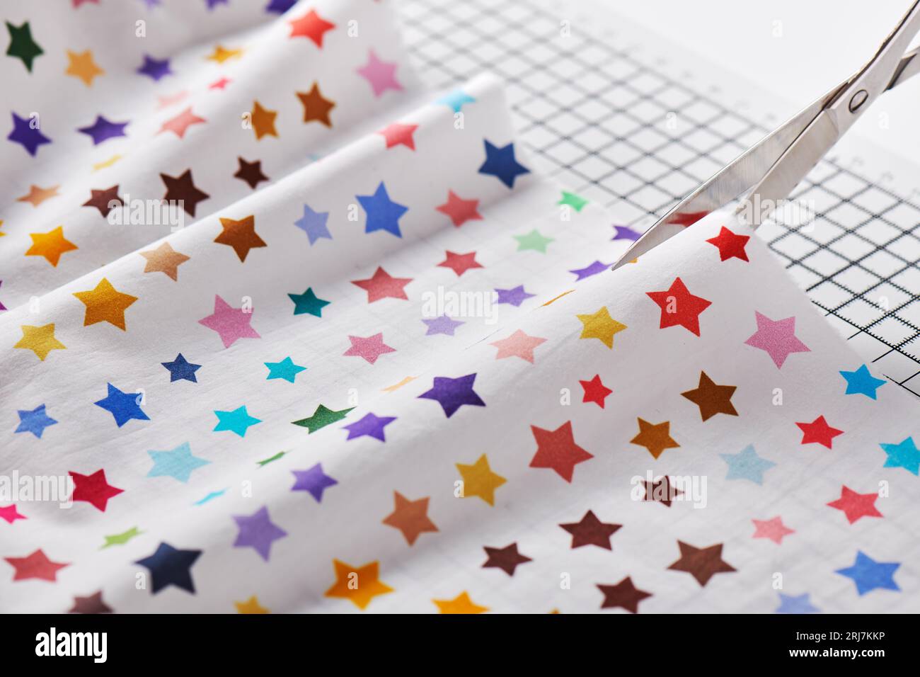 Process cutting fabric with a pattern of colorful stars by scissors on ...