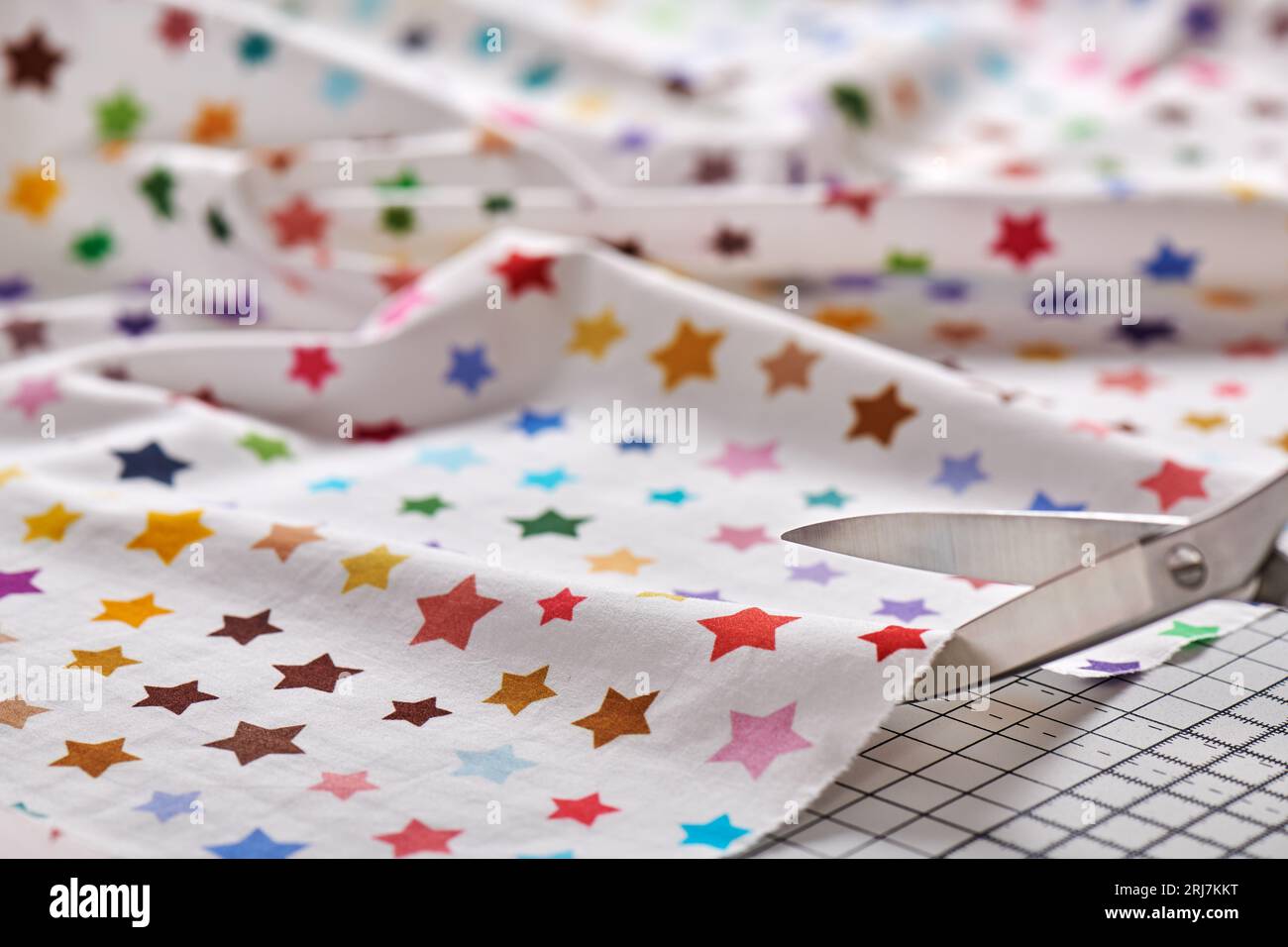 Process cutting fabric with a pattern of colorful stars by scissors on ...