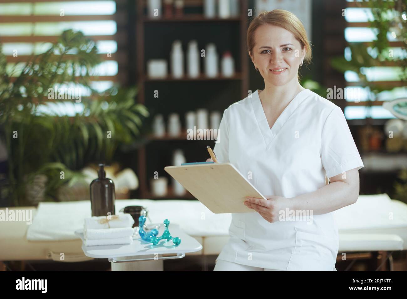 Healthcare time. happy massage therapist woman in massage cabinet with clipboard Stock Photo - Alamy