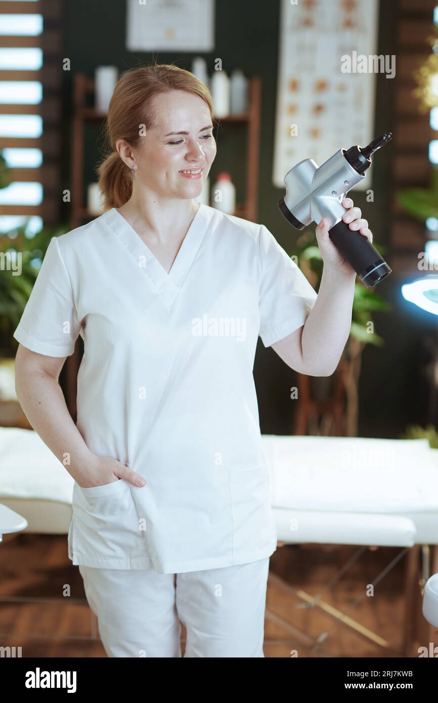 Healthcare time. happy female medical massage therapist in spa salon with massage pistol Stock ...