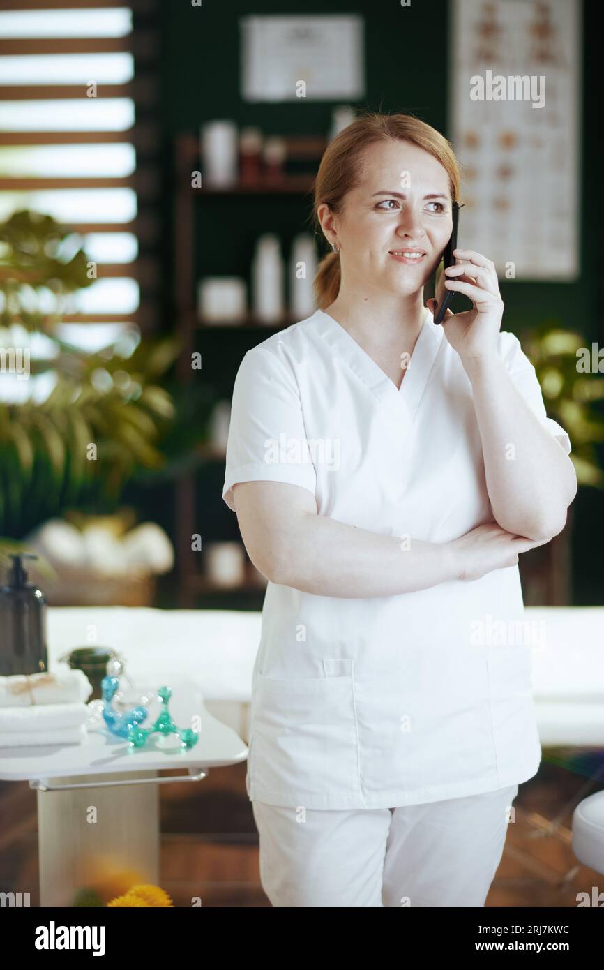 Healthcare time. happy female massage therapist in spa salon talking on ...