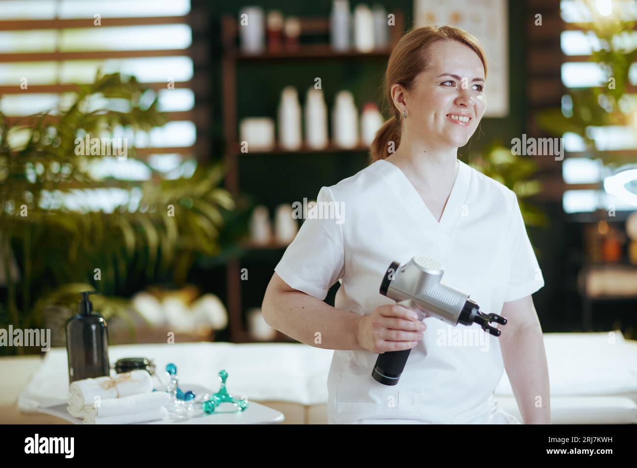 Healthcare time. happy female medical massage therapist in spa salon with massage pistol Stock ...