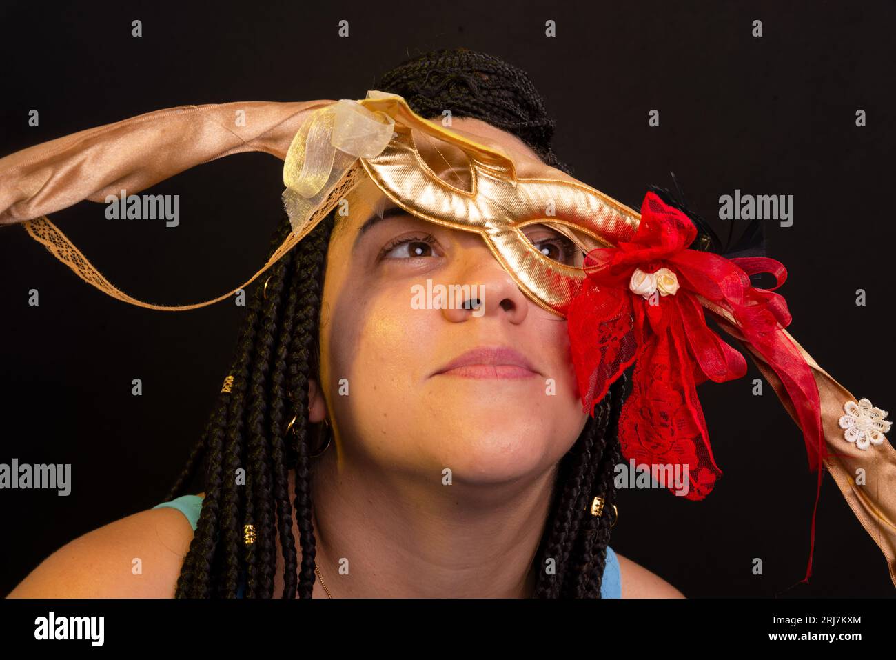 Beautiful woman with braids in her hair putting a mask on her face ...