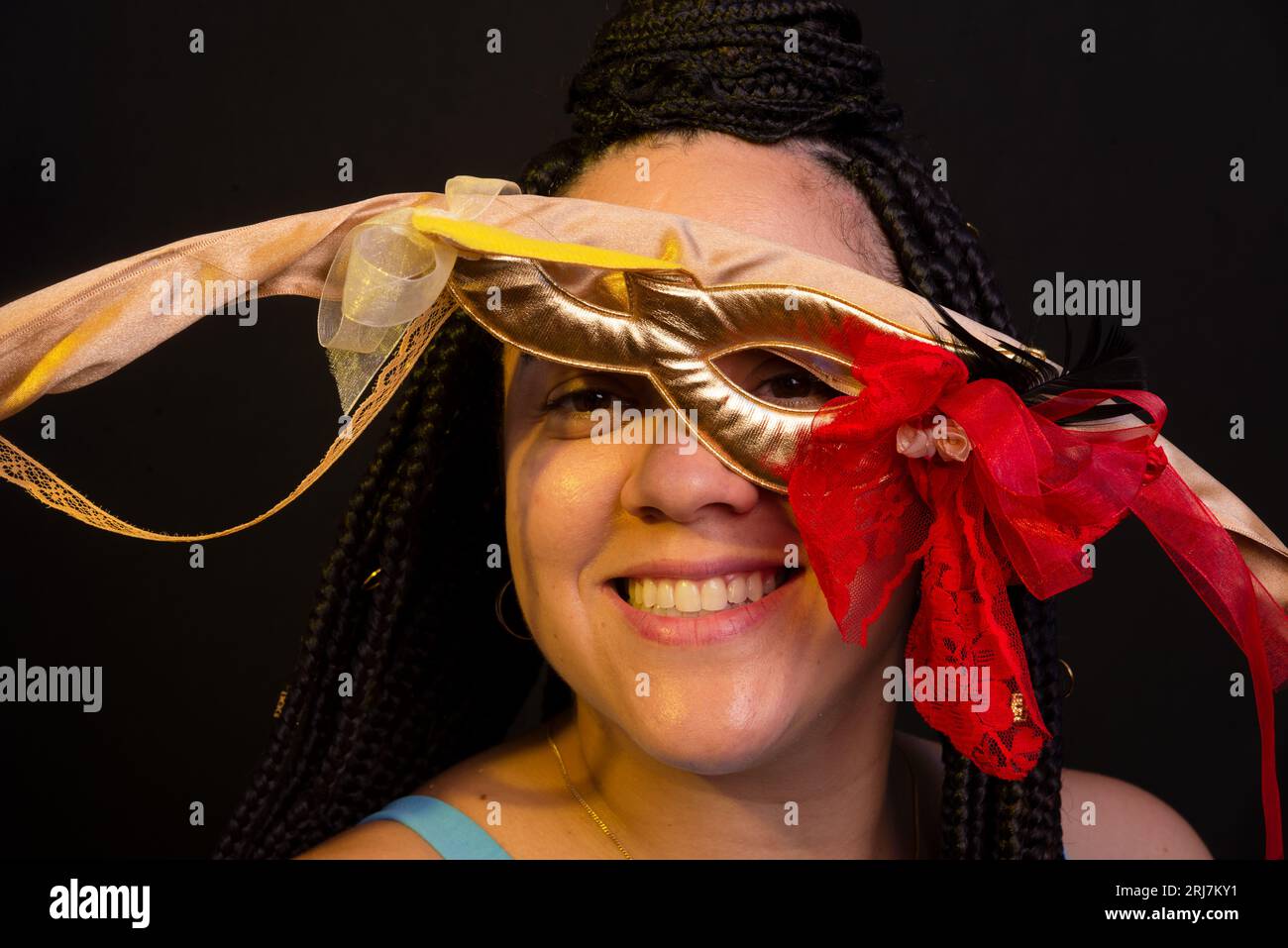 Beautiful woman with braids in her hair putting a mask on her face ...