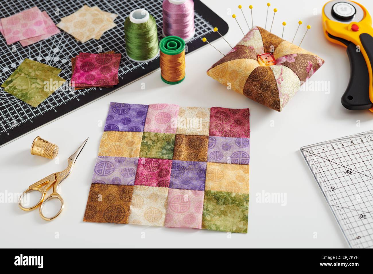 Quilting block from bright square pieces of fabrics, pincushion, stacks ...