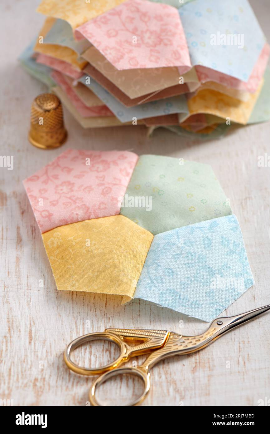 Stitched quilting block from four pentagons, scissors, thimble, pile of ...