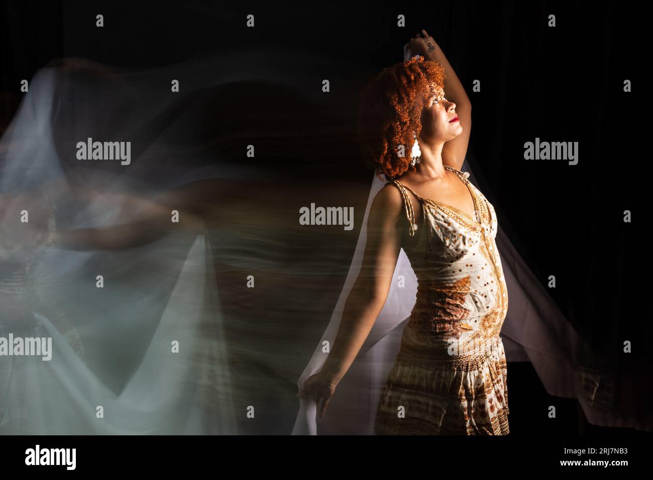 Low-speed shot of a beautiful woman with curly red hair doing movements ...