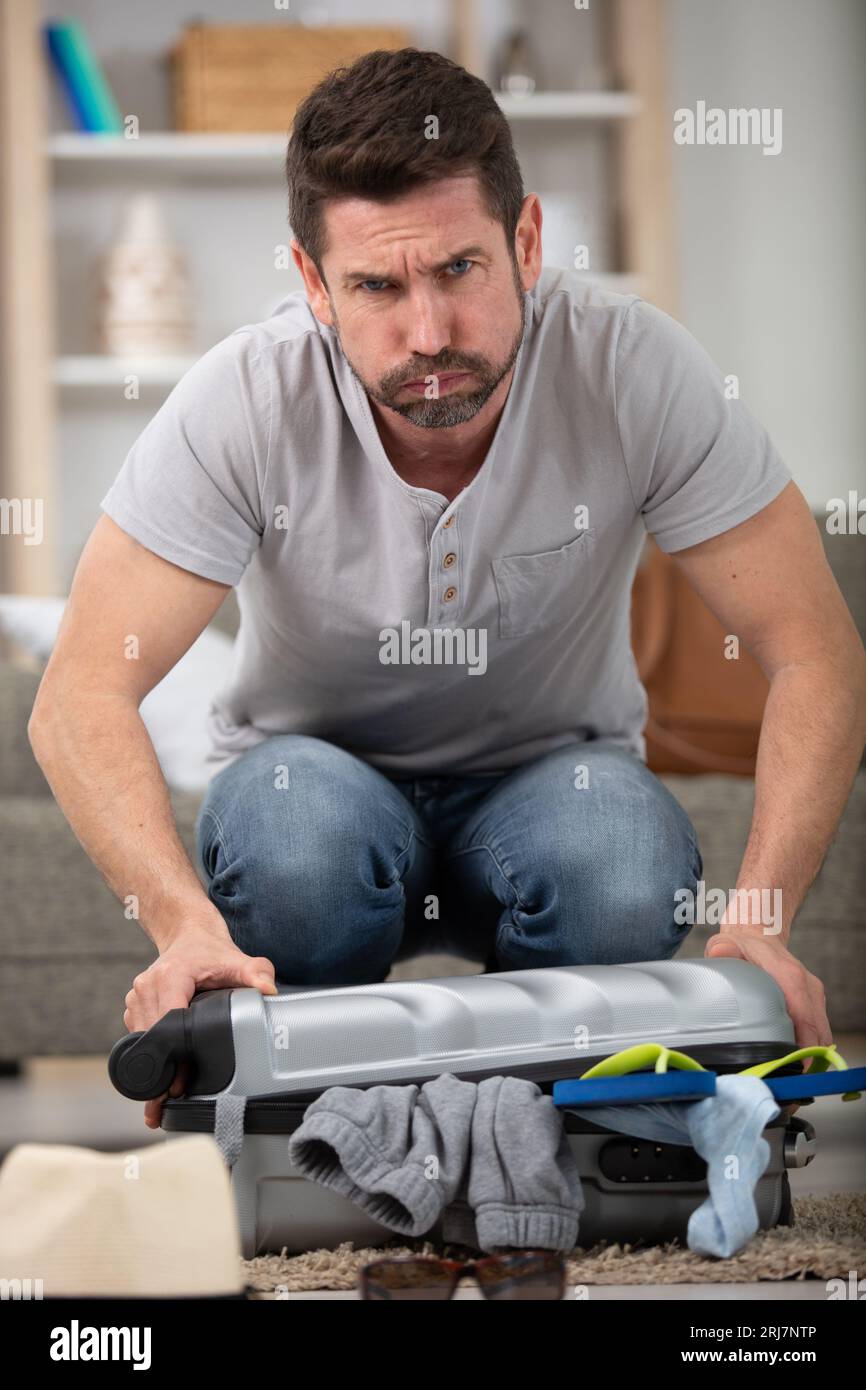 angry man tries to packing suitcase Stock Photo - Alamy