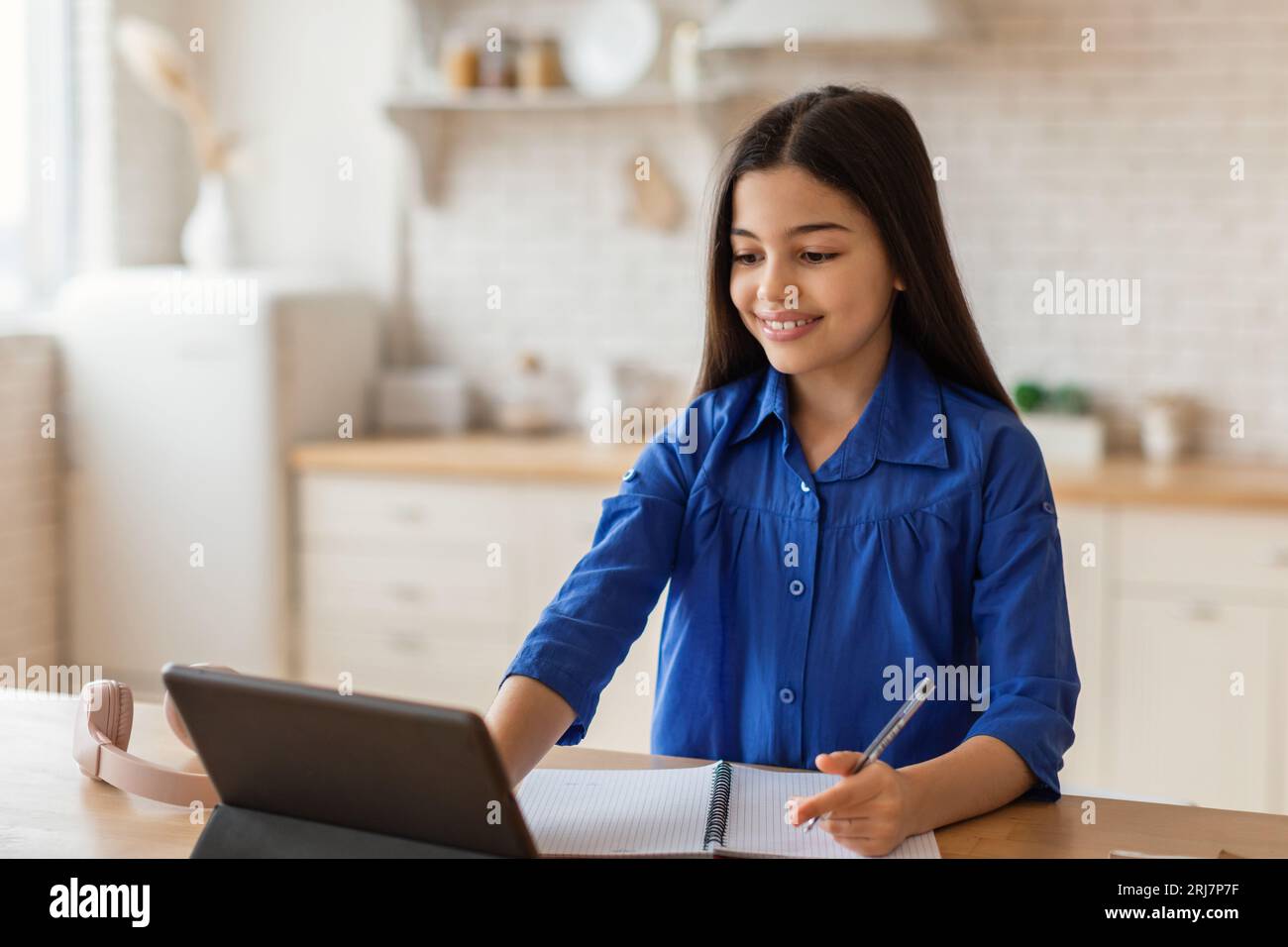 Happy school learner girl using digital tablet taking notes indoors ...