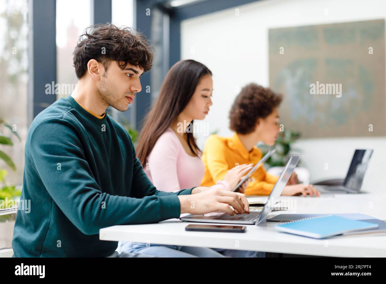 Multiracial male and female students studying for test, making homework ...