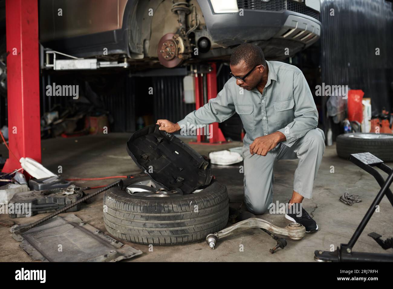 Mechanic checking car engine cover when working in garage Stock Photo ...