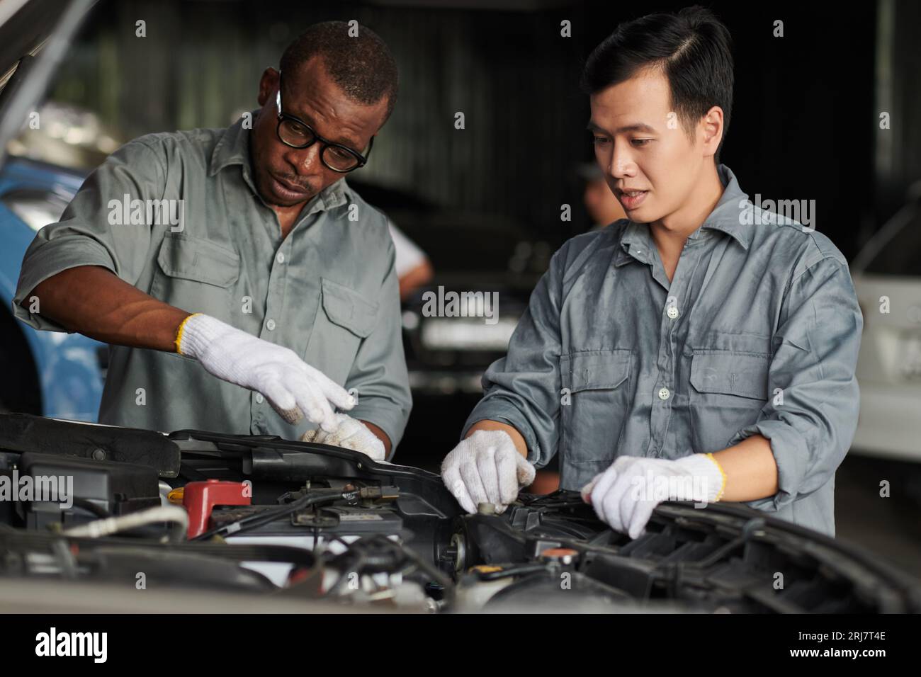 Car mechanics discussing the best way to repair engine Stock Photo - Alamy