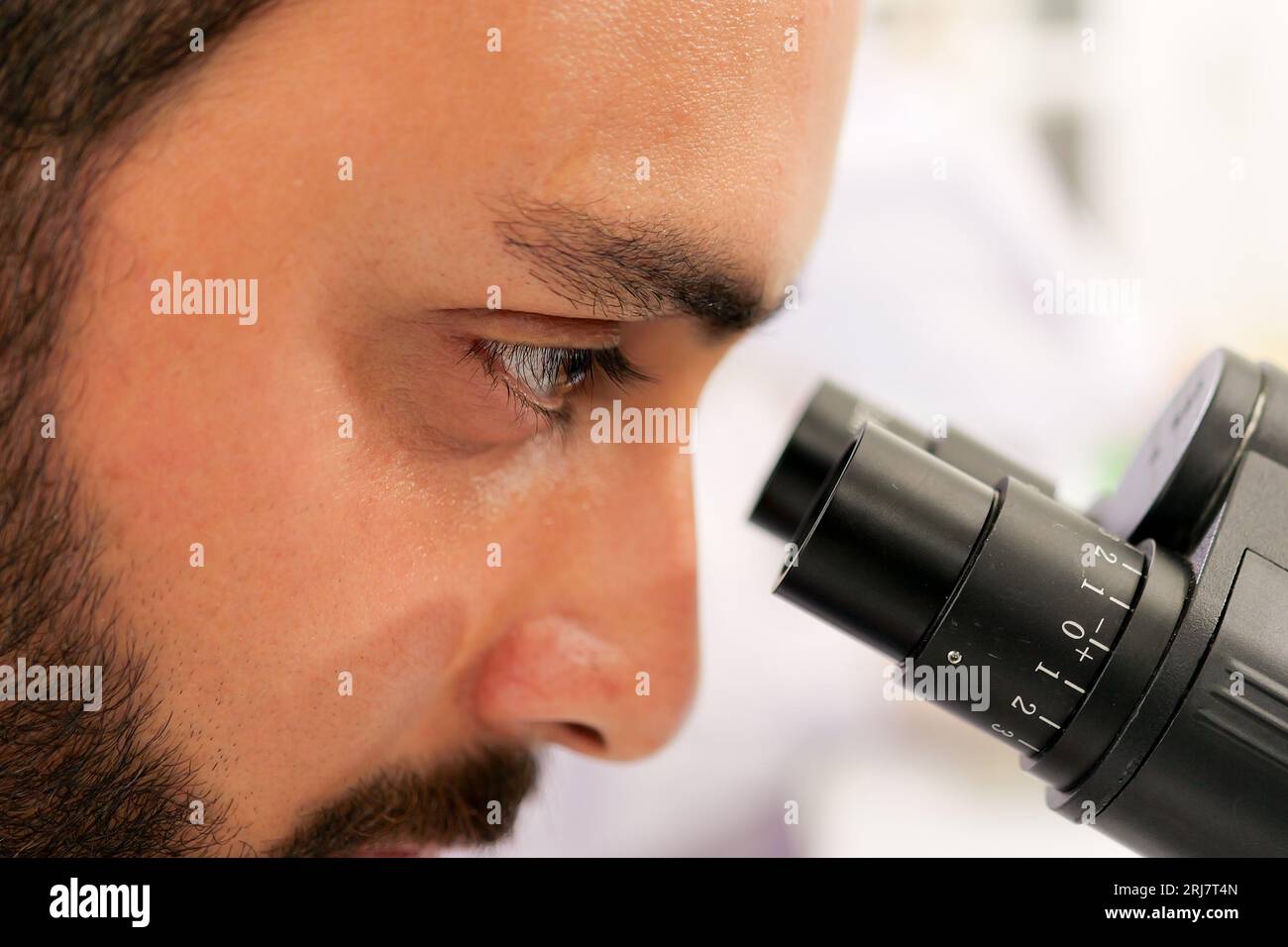 Professional male scientist looking through microscope in laboratory ...