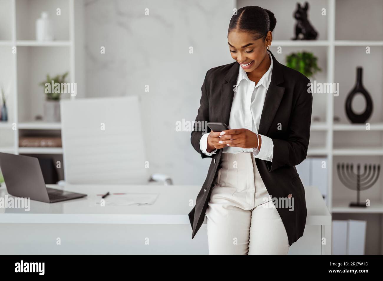 Happy black female entrepreneur in formal wear reading message on ...