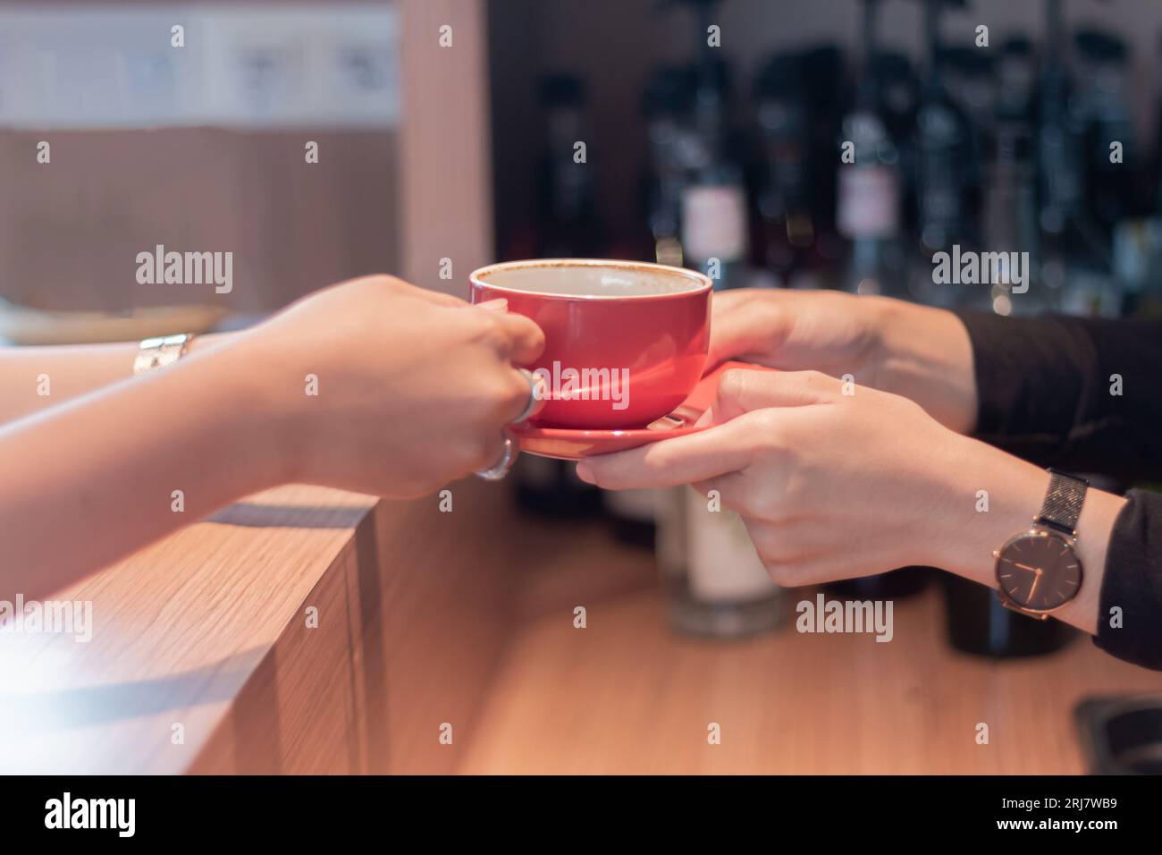 A beautiful Asian barista handing a cup of coffee to customers who wait ...
