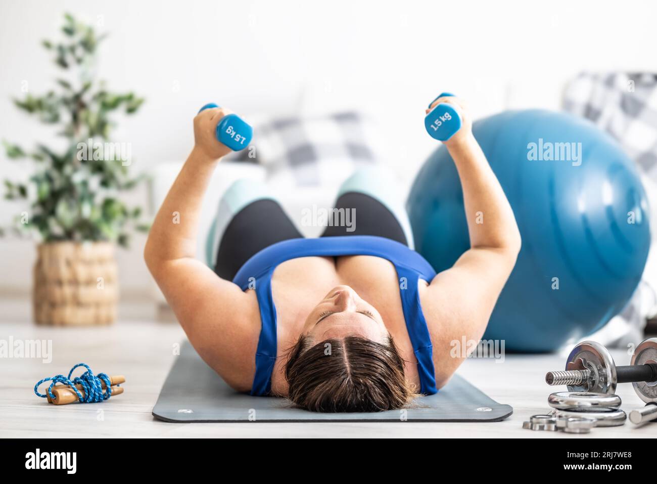 Overweight lady doing sports exercise in living room. He lies on the ...