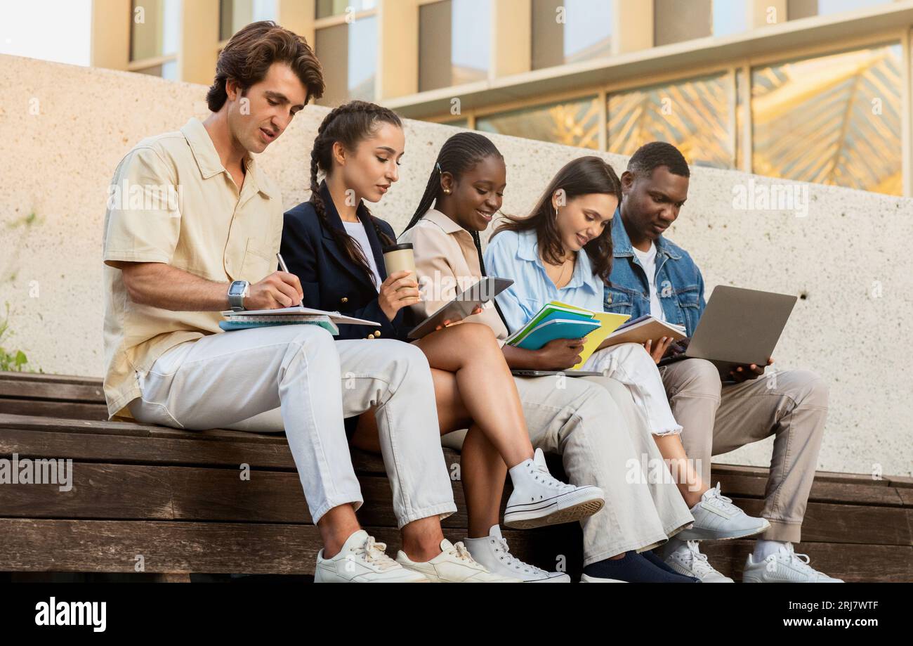 Multicultural group of students sitting at university campus, getting ...