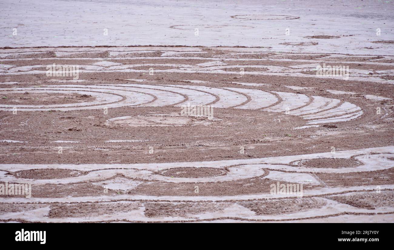 Circular patterns and curved lines drawn into the sand on the beach ...