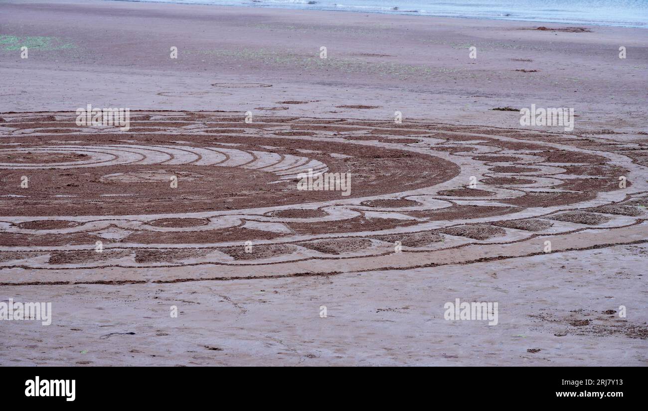 Circular patterns and curved lines drawn into the sand on the beach ...