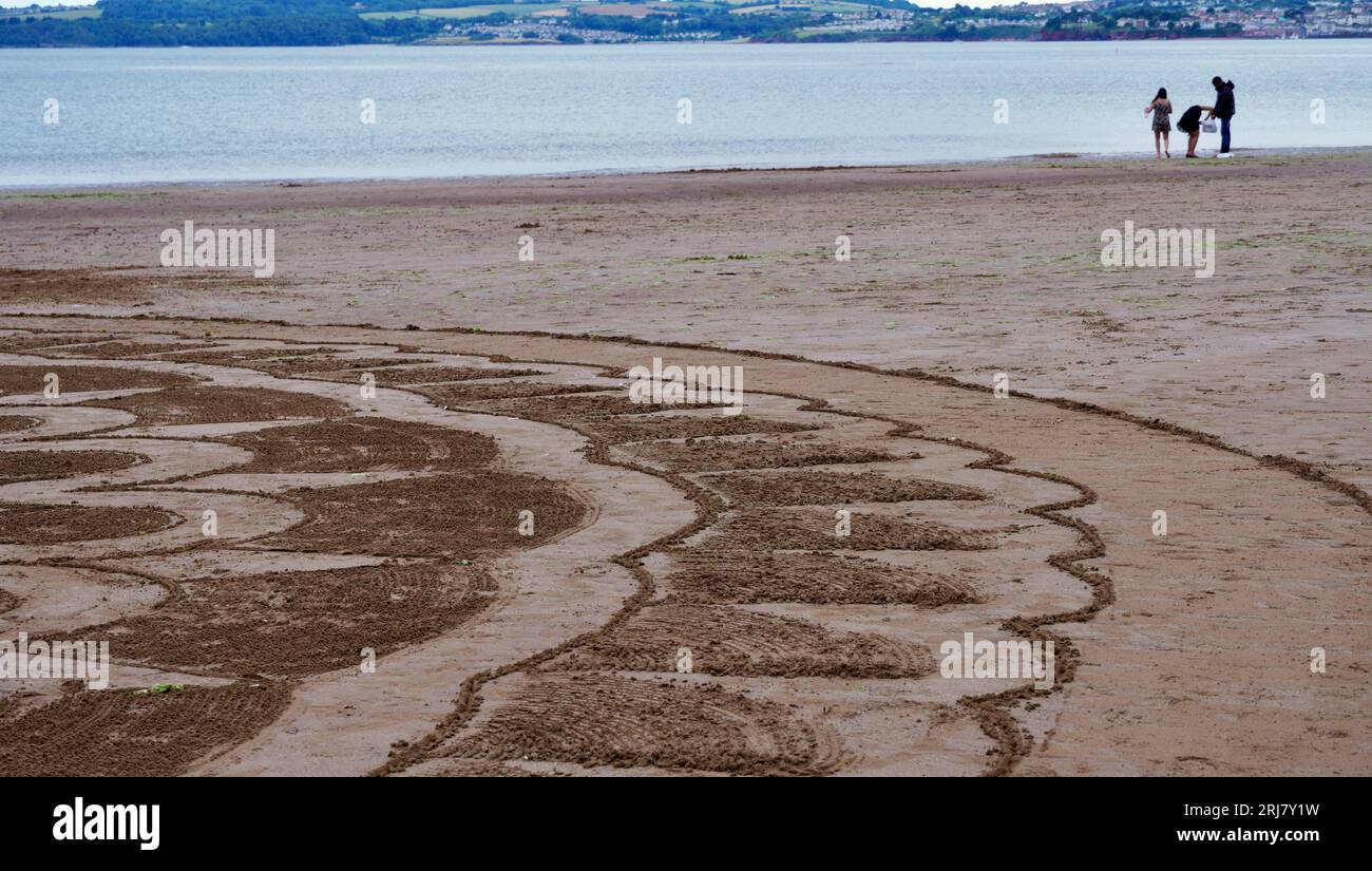 Circular patterns and curved lines drawn into the sand on the beach ...