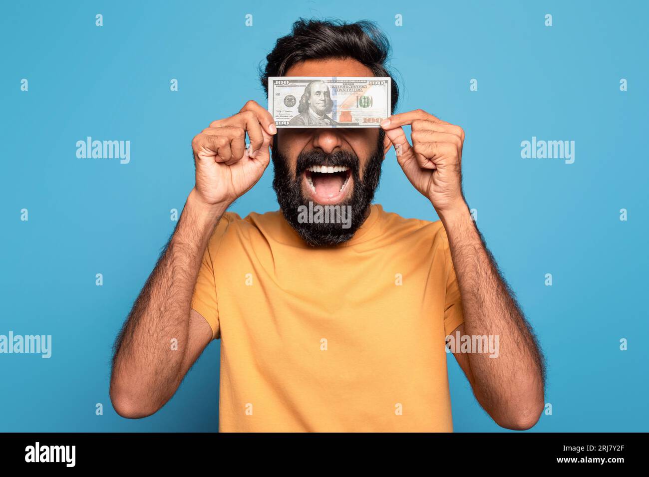 Easy money. Excited indian man holding dollar banknote and cover eyes ...