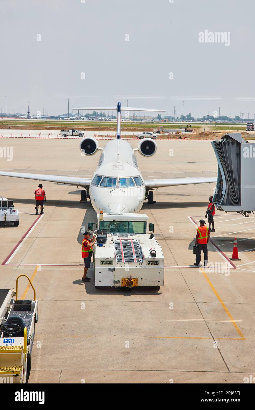 Ground vehicle pulled up to nose of plane being guided away from ...