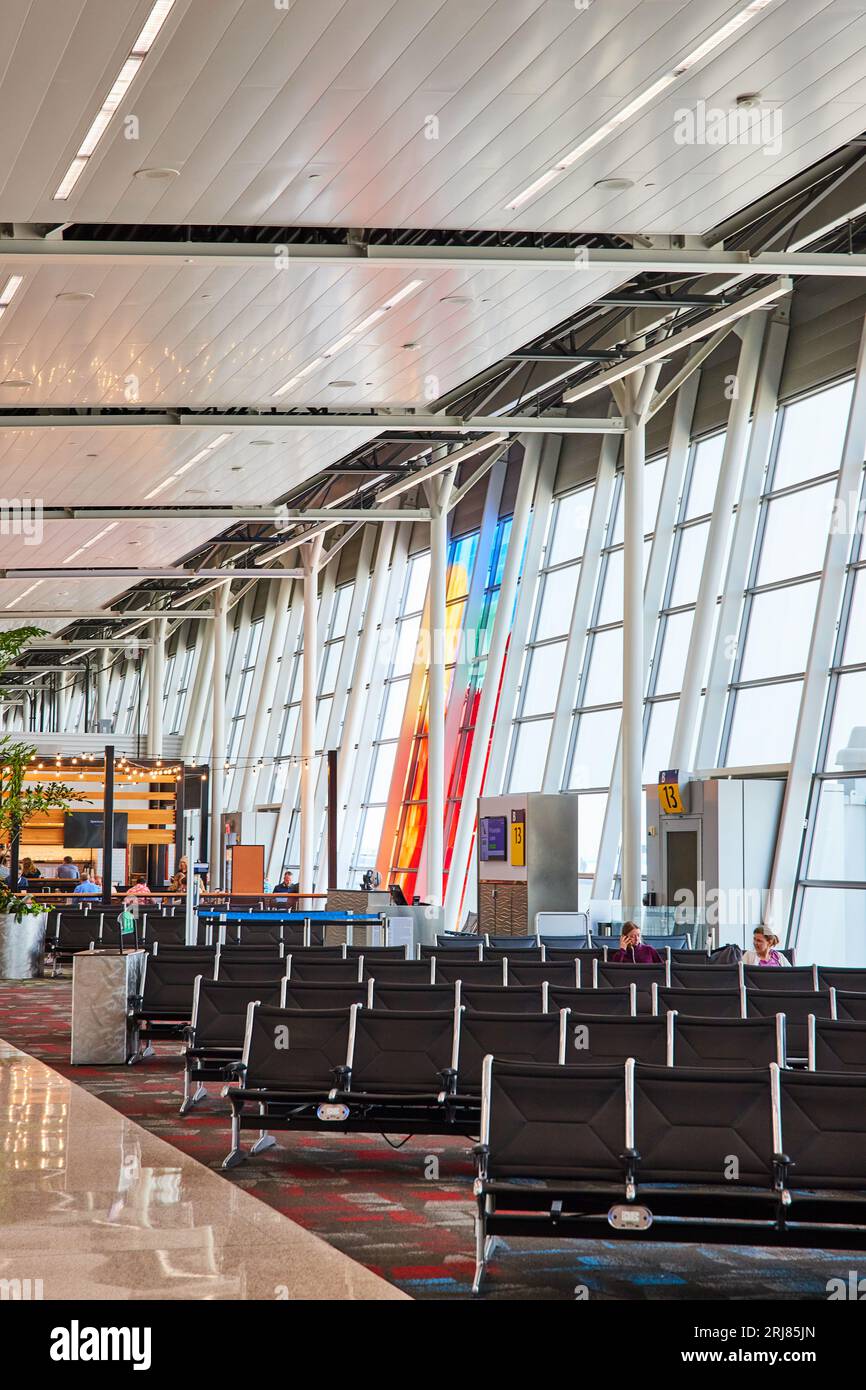Airport terminal 13 with mostly empty seating and windows with white ...