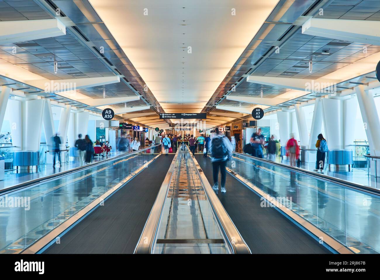 Two moving walkways with people moving through generic airport under ...