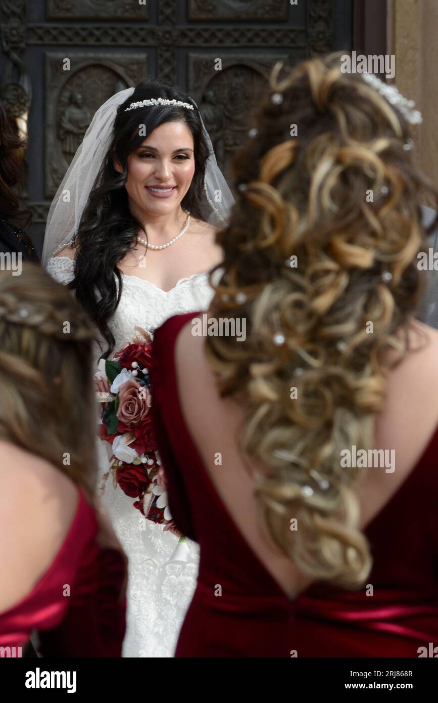 A bride and groom and bridesmaids stand in front of a church after the ...