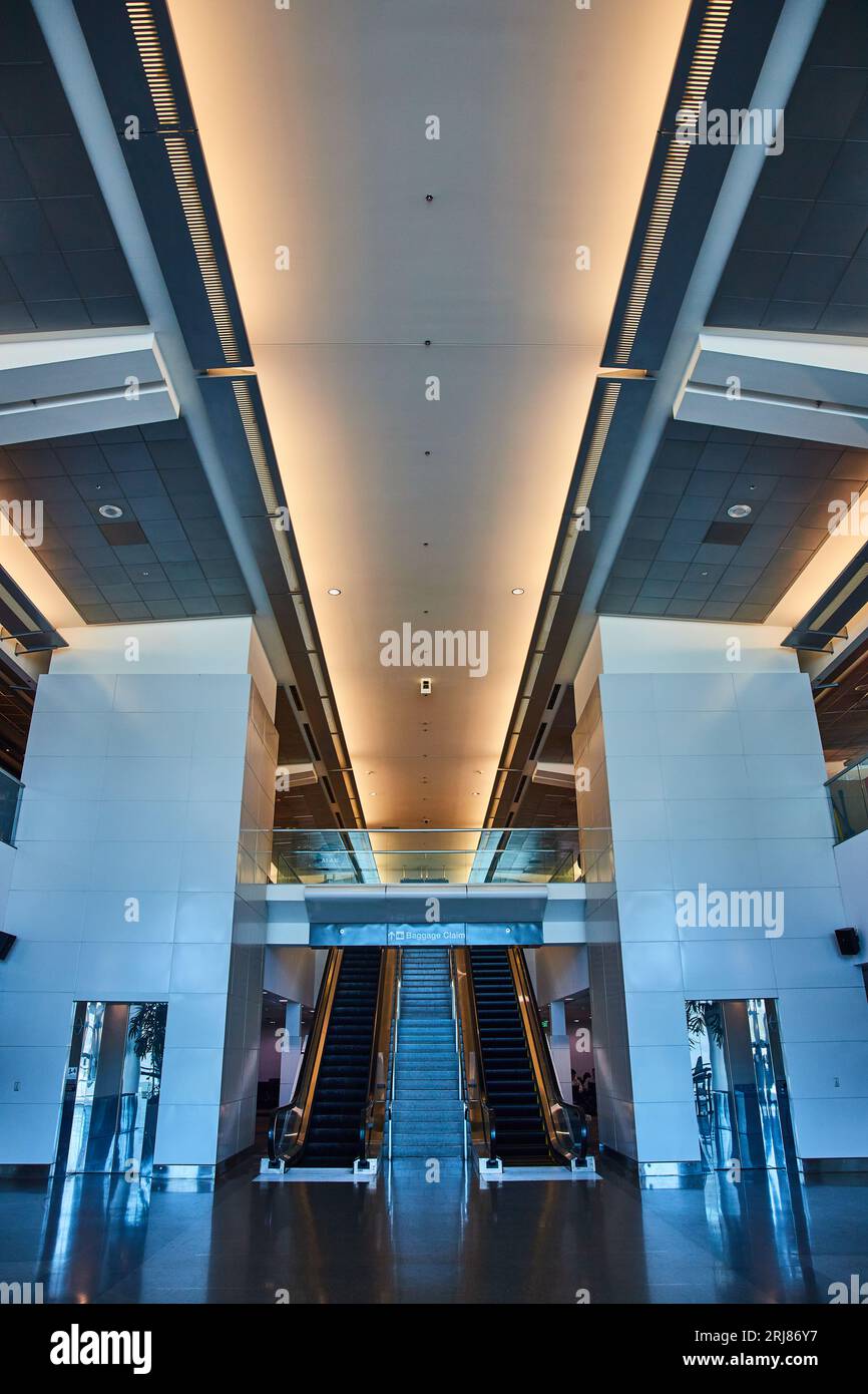 Empty symmetrical airport hallway with stairs framed by escalators and ...