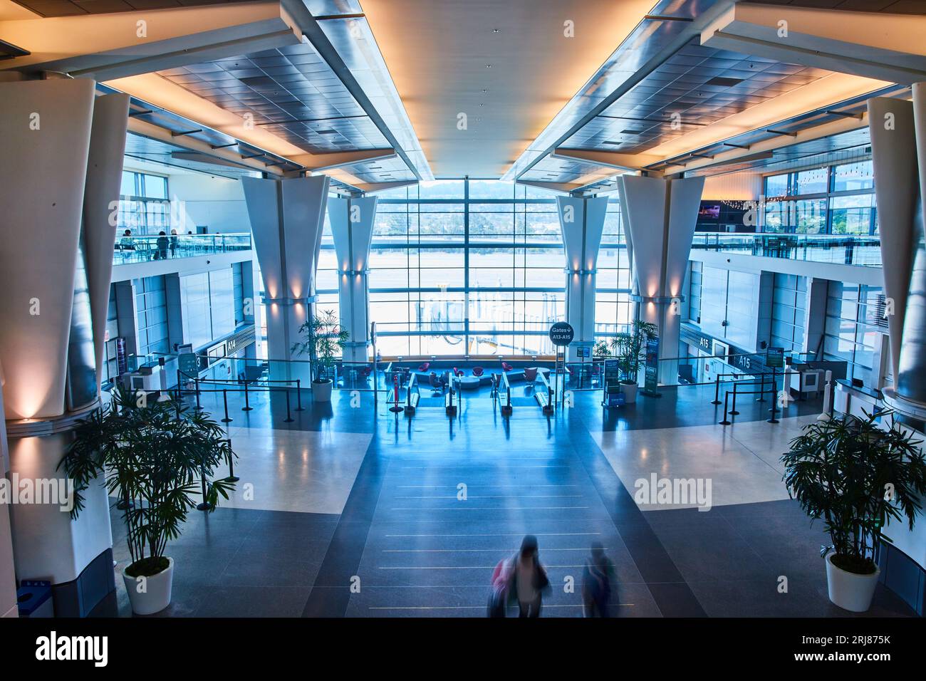 Open airport interior with blue and cream lighting and bright light ...