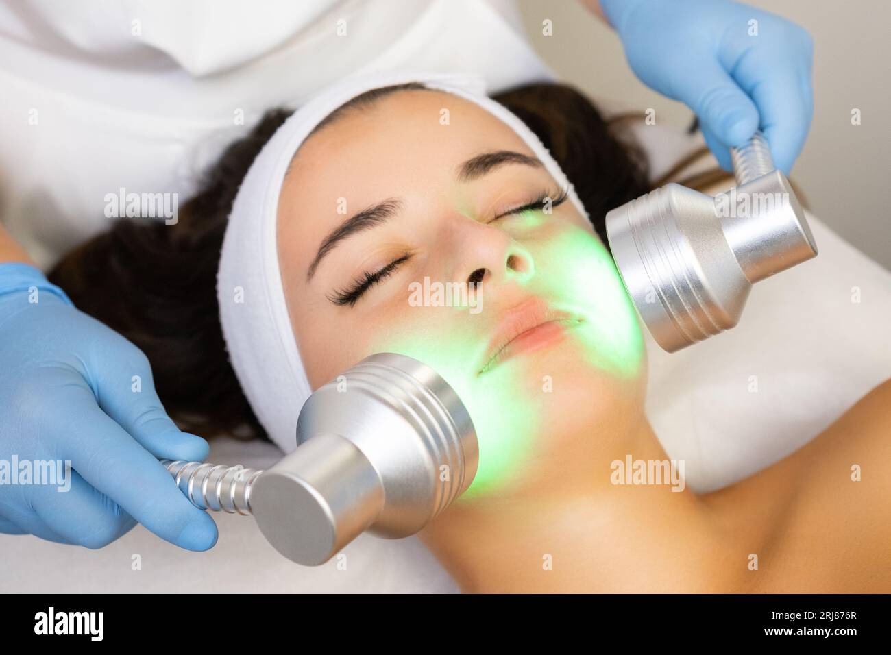 Expert makes light therapy procedure of woman face with contemporary ...