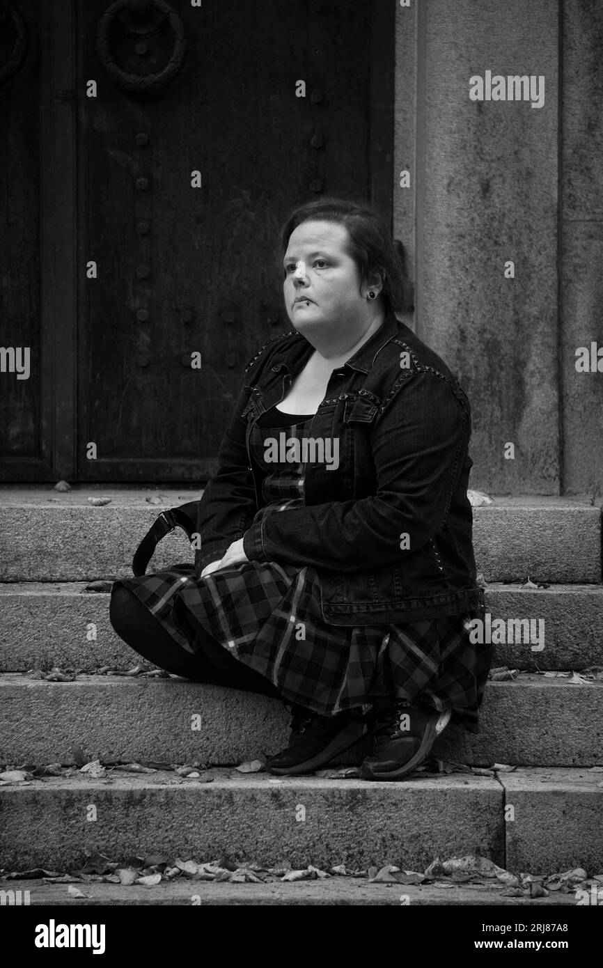 A woman sitting in step in front of a gate Stock Photo - Alamy