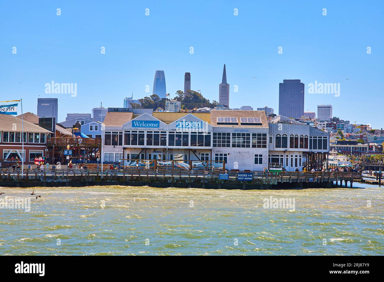 Welcome Pier 39 banner on buildings with distant Coit Tower and San ...