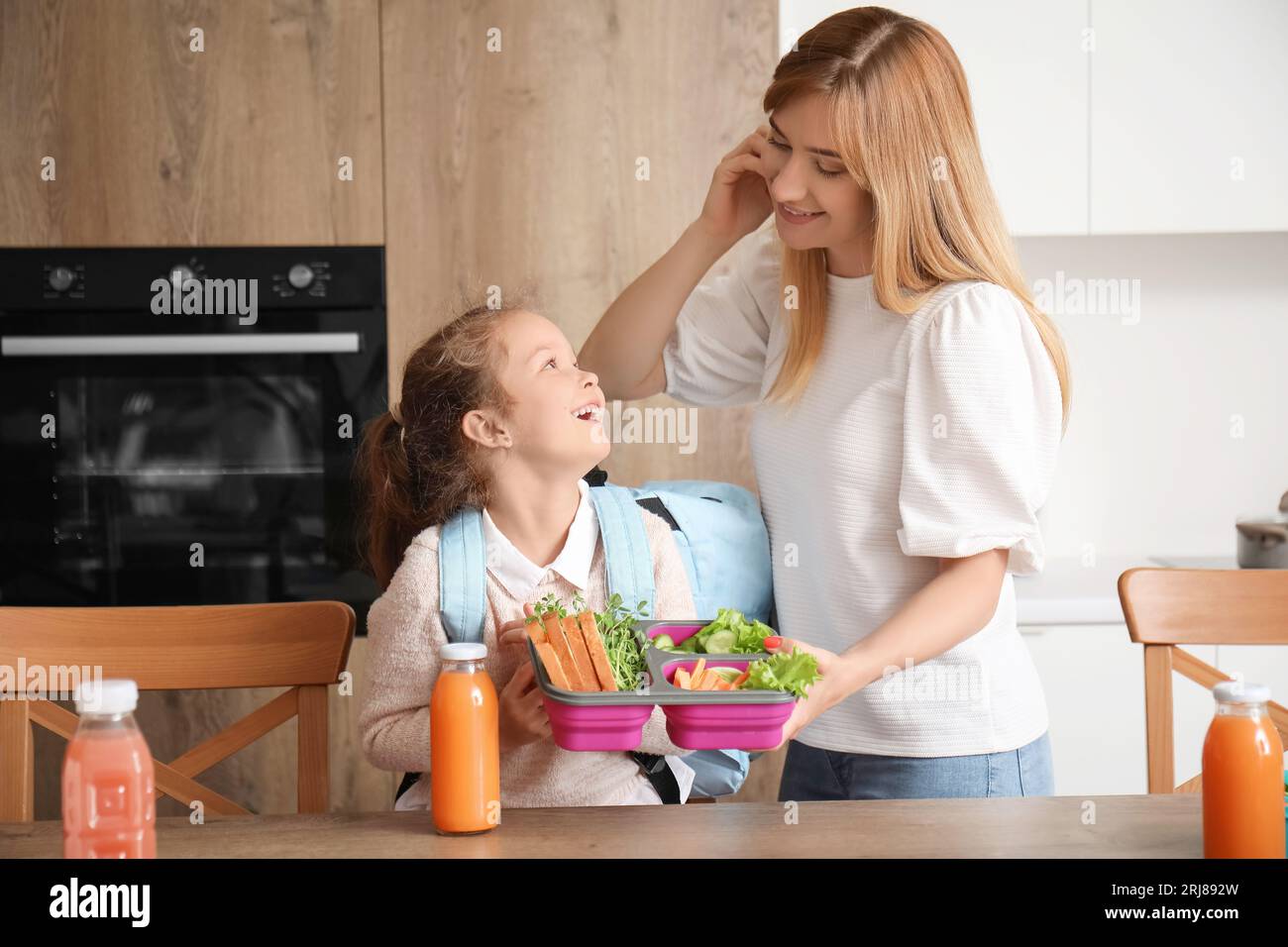 Mother packing school lunch for her little daughter in kitchen Stock ...