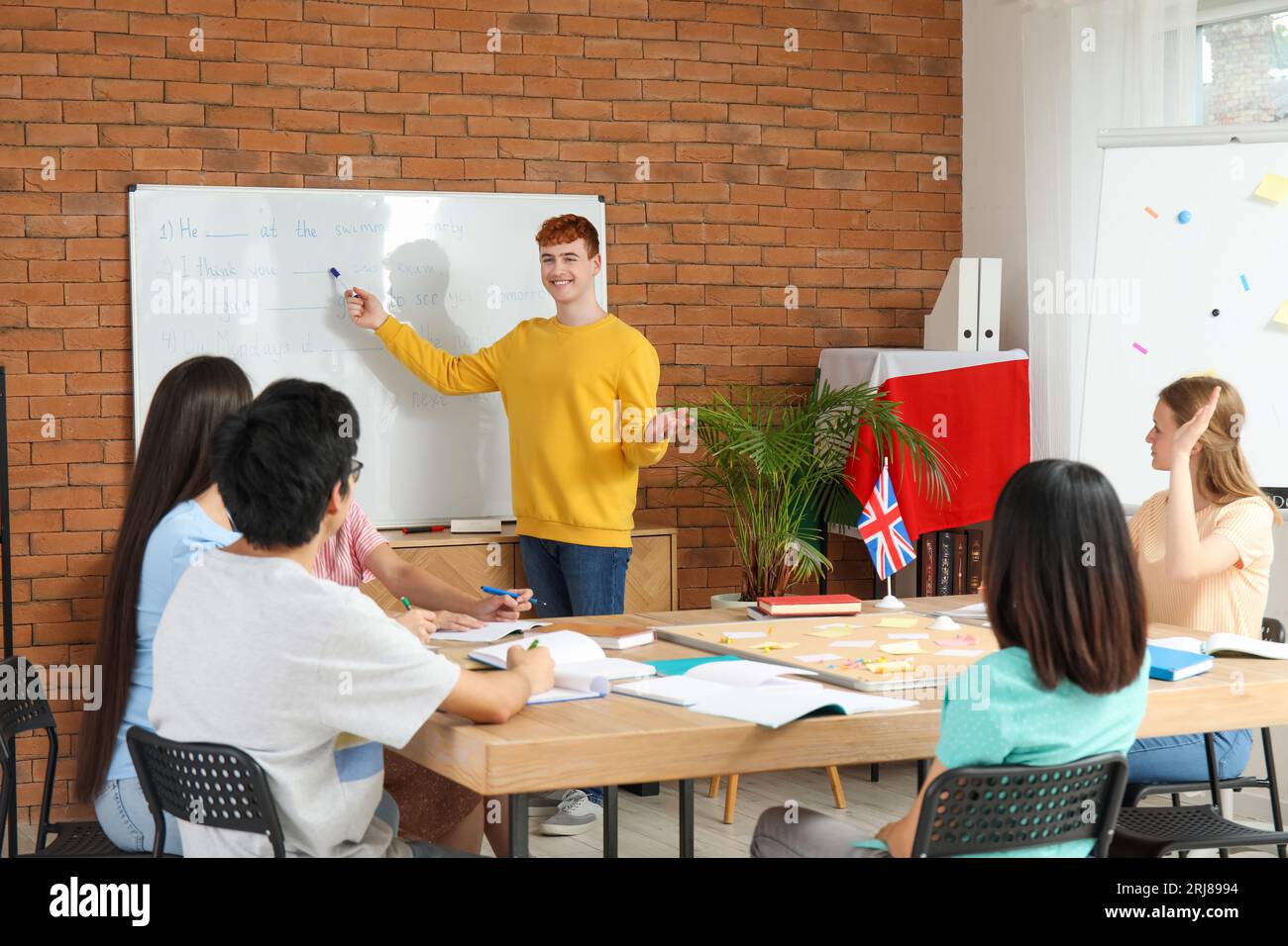Male teacher conducting lesson to young students at language school ...