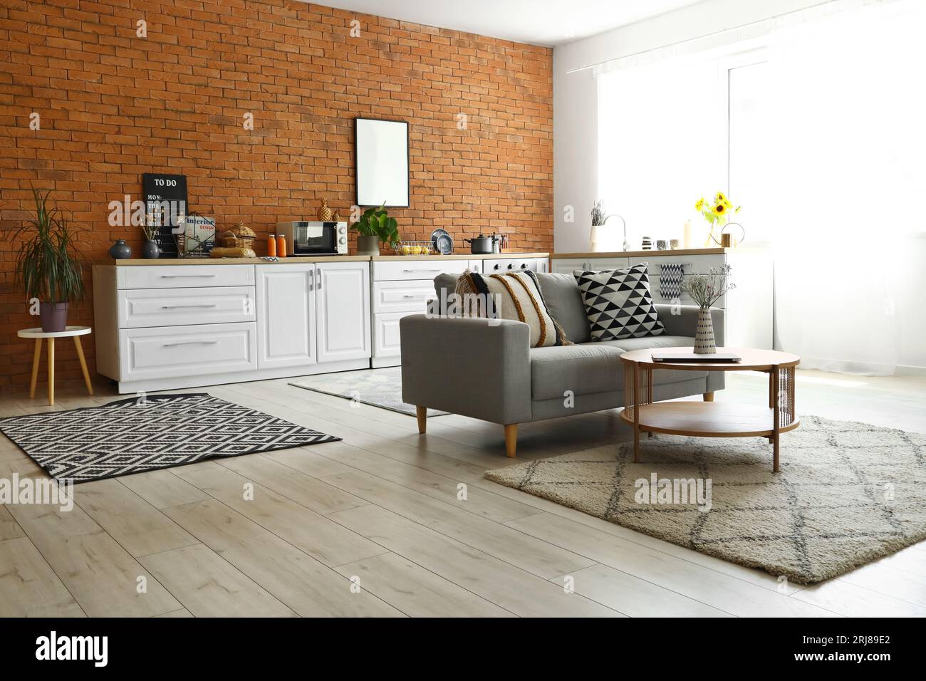 Interior of modern open space kitchen with grey sofa, coffee table and ...