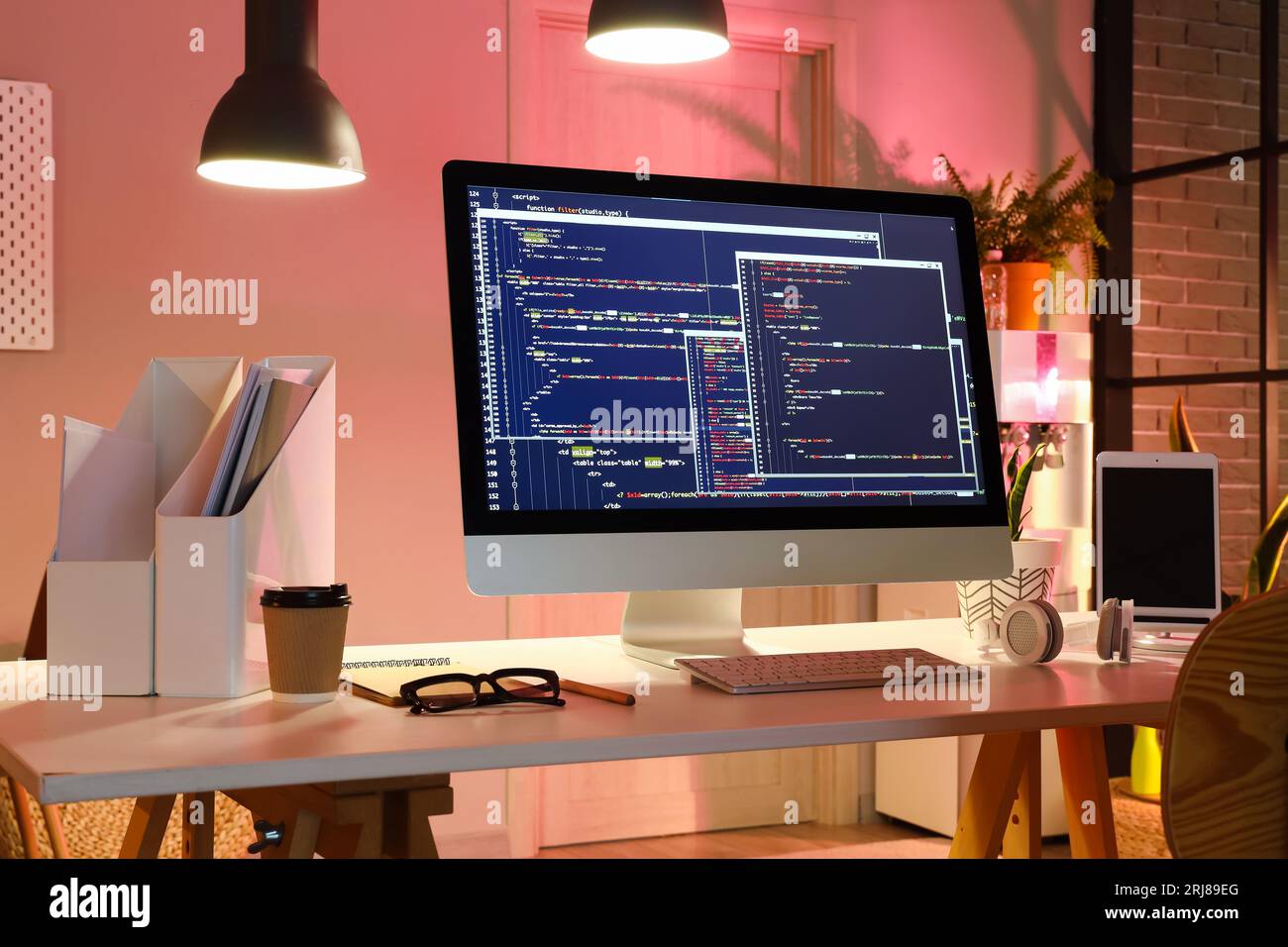 Programmer's workplace with devices in interior of dark office Stock ...