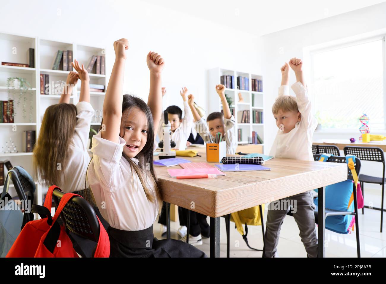 Happy little school children in classroom during lesson Stock Photo - Alamy