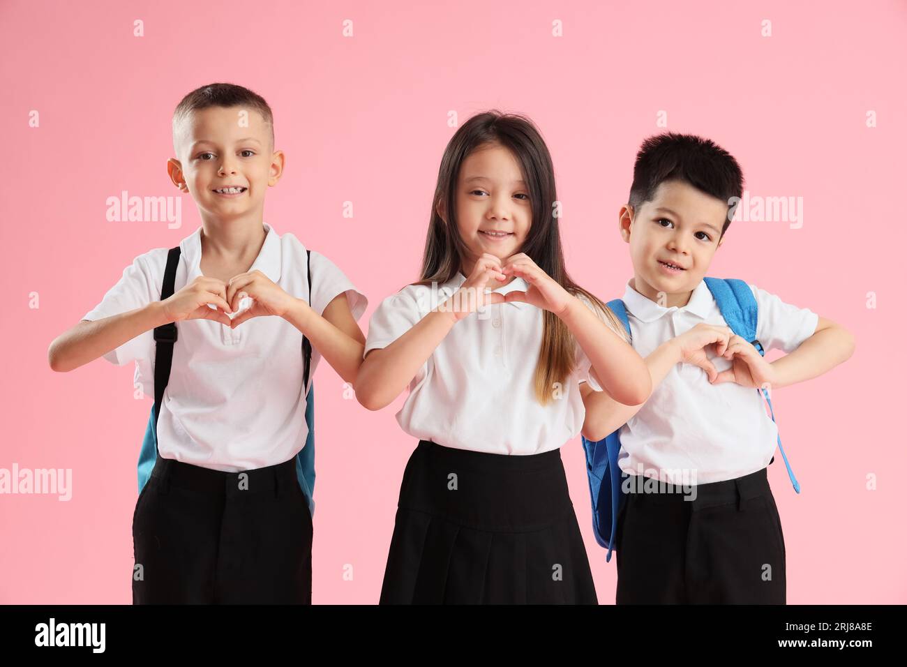 Little school children making heart shape with their hands on pink ...