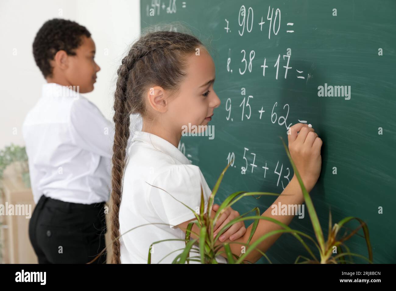 Little classmates writing on chalkboard in classroom Stock Photo - Alamy