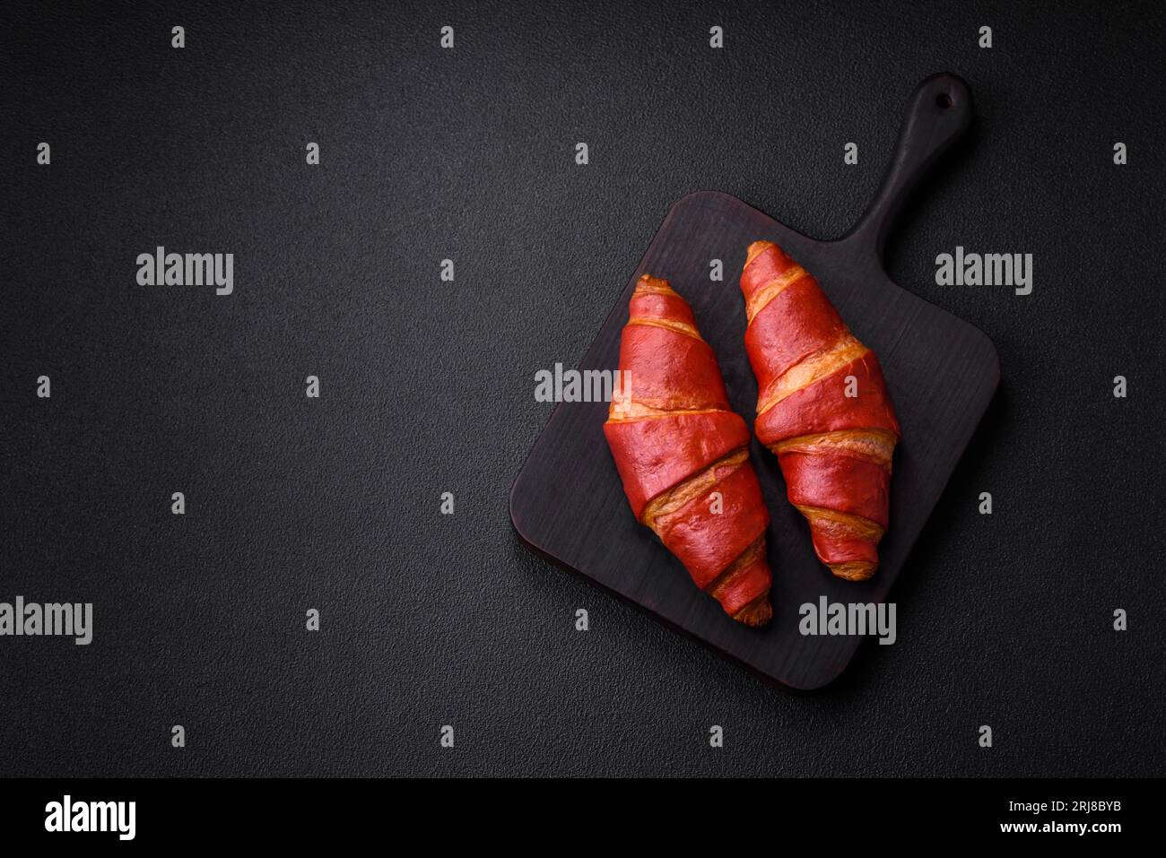 Delicious sweet crunchy red croissant with cream filling on dark ...