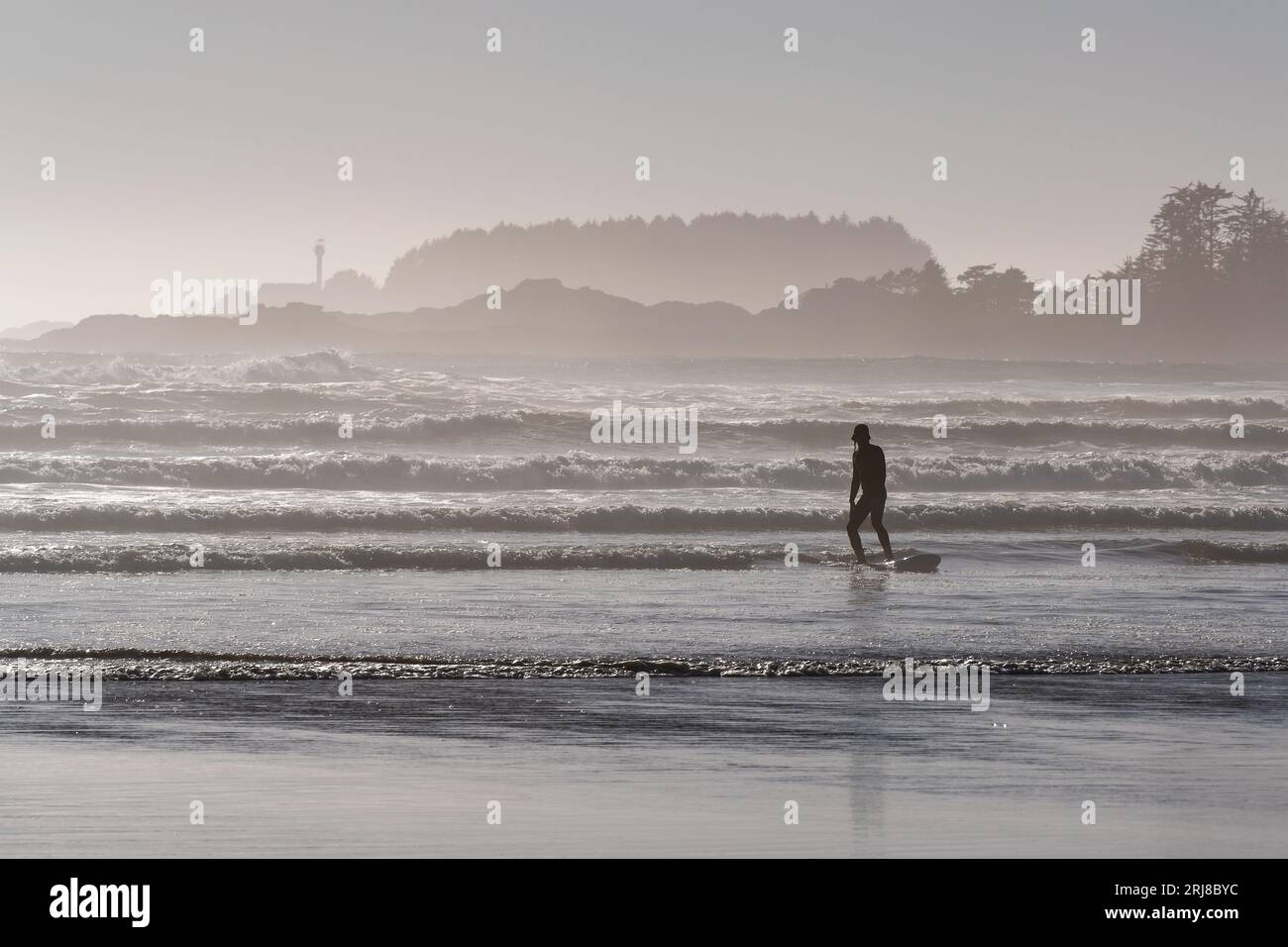 Surfer silhouette in the strong waves on Cox Bay Beach of Tofino with ...