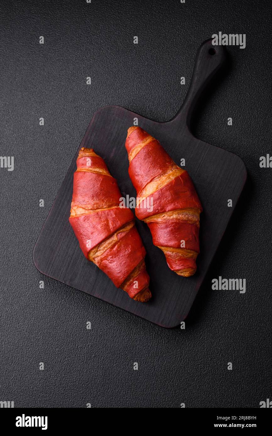 Delicious sweet crunchy red croissant with cream filling on dark ...