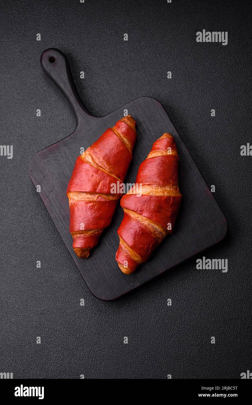 Delicious sweet crunchy red croissant with cream filling on dark ...