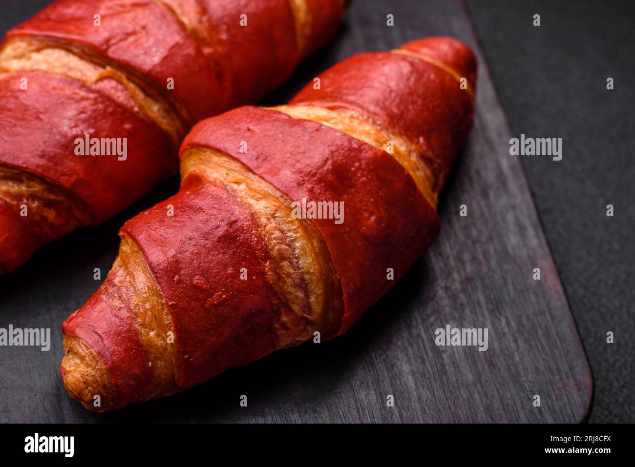 Delicious sweet crunchy red croissant with cream filling on dark ...