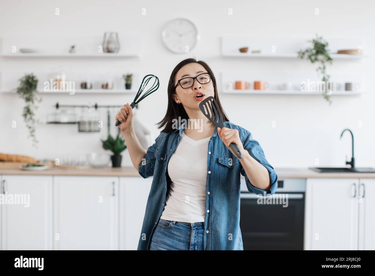 Asian female having fun with whisk while cooking at home Stock Photo ...