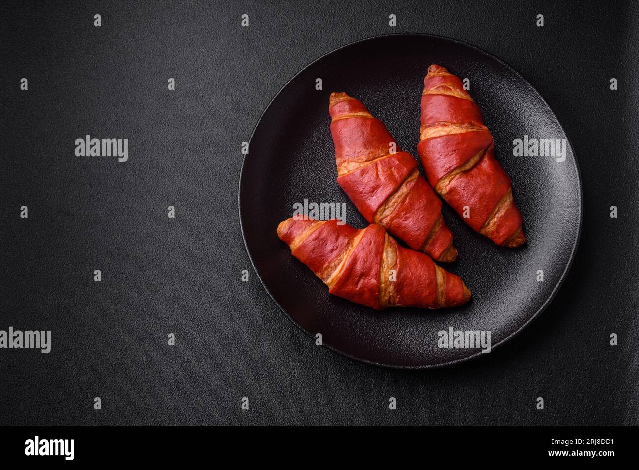 Delicious sweet crunchy red croissant with cream filling on dark ...