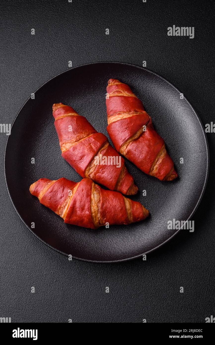 Delicious sweet crunchy red croissant with cream filling on dark ...