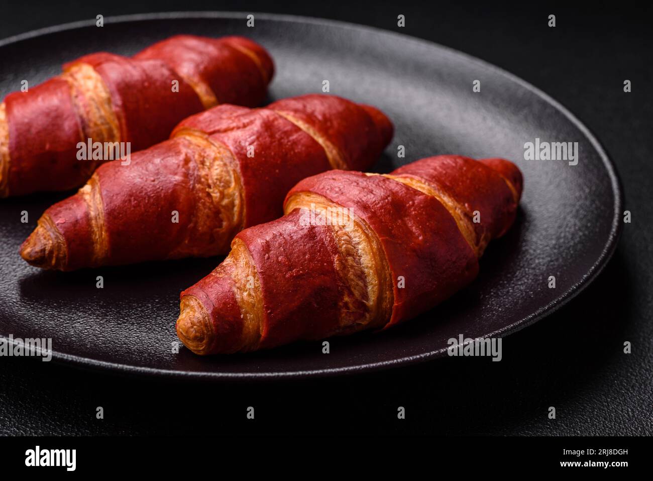 Delicious sweet crunchy red croissant with cream filling on dark ...